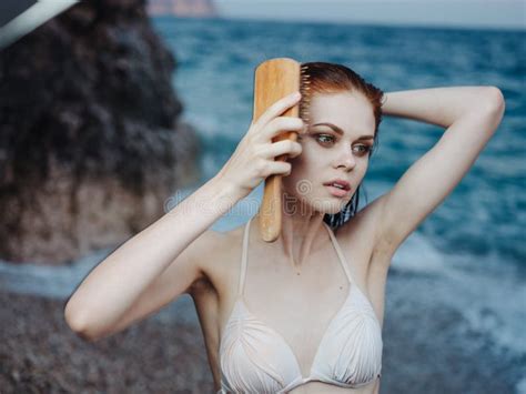 A Beautiful Woman In A Bathing Suit Combs The Hair On Her Head In