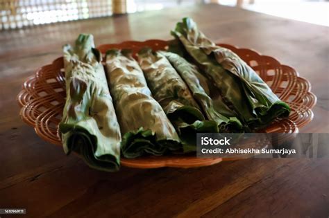 고등어와 밀가루로 만든 생선 케이크를 바나나 잎으로 감싼 인도네시아 전통 구운 어묵인 오탁오탁 텡기리가 나무 테이블 위의 접시에 담겨 제공됩니다 0명에 대한 스톡 사진 및