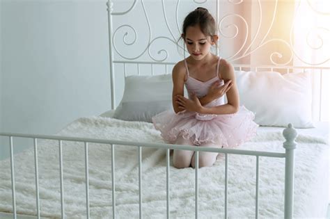 귀여운 분홍색 드레스 어린 소녀 9 년 집에서 침실에서 흰색 침대와 발레를 춤 발레 발레리나 어린 소녀는 방에서 발레 춤을 연습