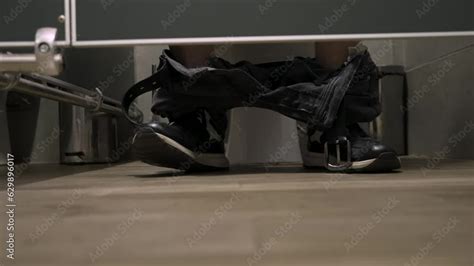 A Man Pulls Down His Pants In The Office Toilet And Sits On The Toilet