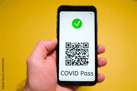 Covid Pass With QR Code On The Screen In Smartphone In Mans Hand On The Yellow Background May
