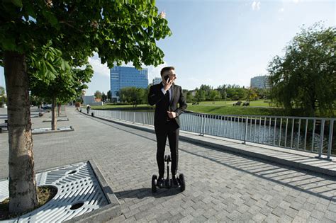 검은 양복을 입은 사업가가 자이로 스쿠터를 타고 전화로 이야기합니다 비즈니스에 대한 스톡 사진 및 기타 이미지 비즈니스 35 39세 거리 Istock