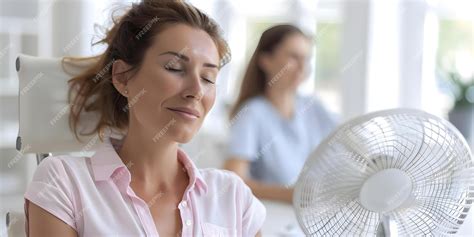 Premium Photo Woman Uses Personal Fan At Desk To Manage Menopausal