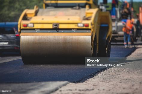 도로 건설 및 수리 작업 중 아스팔트 파버 기계 및 증기 도로 롤러 새로운 도로 건설 현장에서 일하는 근로자 여름에 레이어를