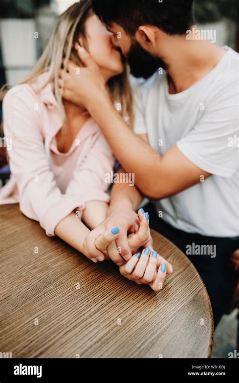 Holding Hands Of A Lovely Couple Embracing And Kissing While Sitting At