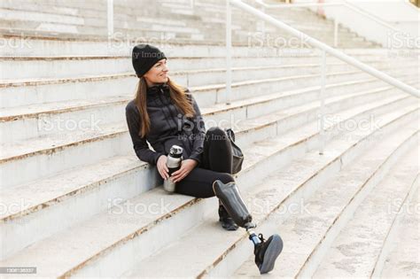 검은 색 스포츠웨어를 입은 행복한 장애인 여성의 사진 보철다리에 앉아 보온병 컵을 들고 있는 보철병 거리에 대한 스톡 사진 및