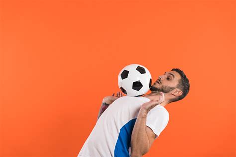 주황색 배경에 고립 된 축구 공으로 트릭을하는 흰색 파란색 셔츠에 집중 된 축구 선수 Championship에 대한 스톡 사진 및 기타 이미지 Championship