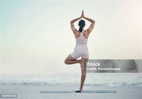 뒤로 균형 잡힌 자세와 요가를 위해 해변에서 여성에 의해 웰빙 선 및 평화 바다 모형에 대항합니다 뒷모습 에너지 운동 및 피트니스 운동을 위해 바다에서 소녀에 의한 서기 및