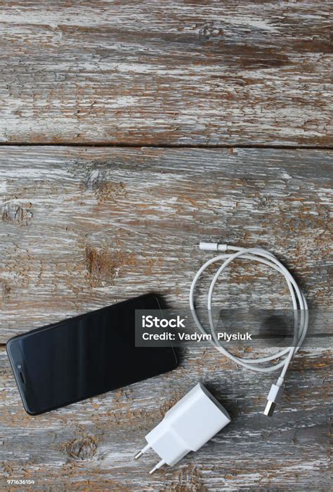 화이트 충전기 그리고 오래 된 나무 배경에 검은색 스마트폰 정보 기술 수평 디지털 사진입니다 빈티지 텍스처에 현대적인 레이아웃입니다 Usb 케이블에 대한 스톡 사진 및 기타