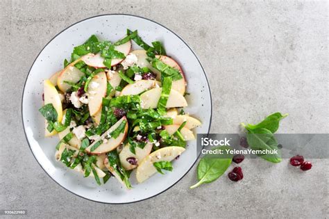 신선한 사과 크랜베리 호두 이탈리아 리 코타 치즈 시금치로 건강 한 과일과 베리 샐러드 나뭇잎 아침 식사 맛 있는 고 영양가 있는 식단 요리입니다 샐러드 그릇에 회색 돌