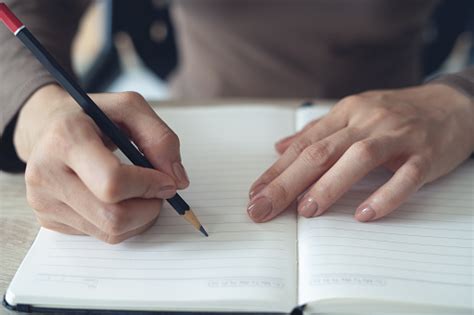 클로즈업 사무실 탁자 위의 종이 공책에 글을 쓰는 연필을 가진 여자의 손 비즈니스 여성은 알림 메모장 비즈니스 및 이벤트 계획 앞보기에 대한 아이디어를 메모합니다 계획에