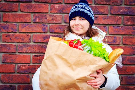 식품 슈퍼마켓 근처의 패키지와 함께 아름 다운 소녀 식료품가 게에서 쇼핑 하는 여자 따뜻한 옷과 모자 야채와 식료품 쇼핑 가방을
