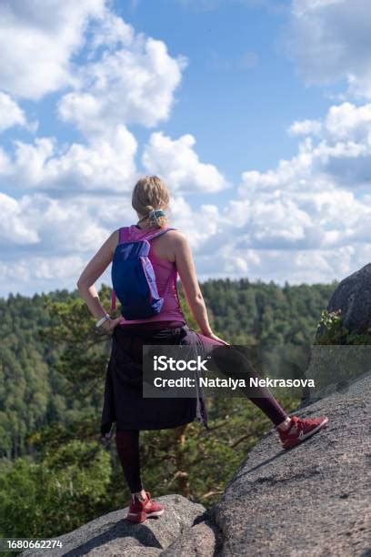 배낭을 메고 운동복을 입은 젊은 활기찬 소녀가 산속의 절벽 가장자리에 서서 구름이 있는 아름다운 풍경을 바라본다 하이킹의 개념 30 34세에 대한 스톡 사진 및 기타 이미지