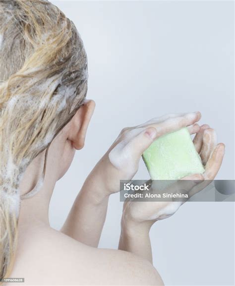 단단한 머리 샴푸 마른 샴푸로 머리카락을 거품을 내는 욕실에있는 금발 소녀의 클로즈업 거품과 엿보기 효과가 많이 있습니다 샴푸에