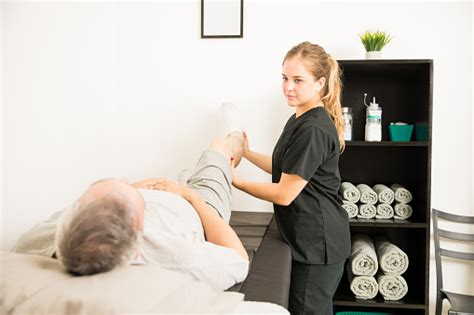 다리 운동으로 통증 완화를 위해 환자를 돕는 물리 치료사 20 29세에 대한 스톡 사진 및 기타 이미지 20 29세 2명 50 59세 Istock