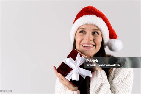 흰색 배경에 고립 된 그녀의 얼굴 근처에 선물 상자를 들고 산타 모자에 아름다운 미소 여자의 초상화를 닫습니다 25 29세에 대한 스톡 사진 및 기타 이미지 Istock