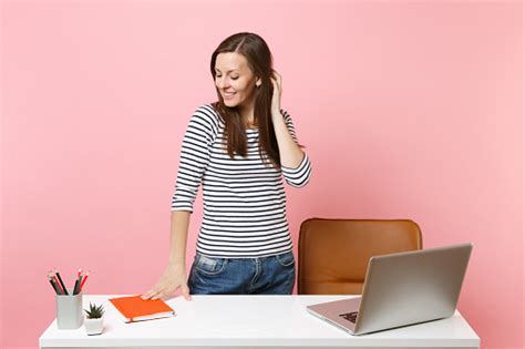 젊은 잠겨있는 여자 작업을 내려다보고 하 고 파스텔 핑크 배경에 고립의 현대 Pc 노트북과 흰색 책상 근처에 서 성과 비즈니스 경력 개념입니다 광고에 대 한 공간을 복사