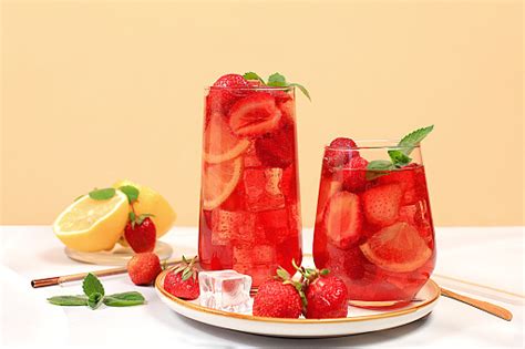 딸기 아이스티 또는 민트 레몬 칵테일은 상쾌한 여름 음료 레시피입니다 가벼운 콘크리트 테이블에 베리 과일 레모네이드가 담긴 안경 디톡스 다이어트와 체중 감량 개념 레스토랑
