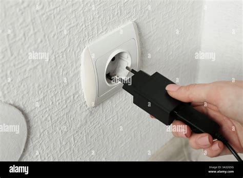 Woman Plugging Usb Power Adapter With Charge Cable Into Electrical Socket Indoors Closeup Stock