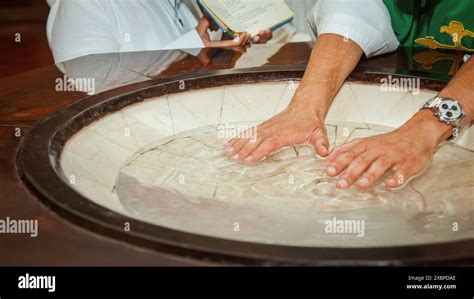 Priest Performing A Water Blessing In A Churchs Baptismal Font During
