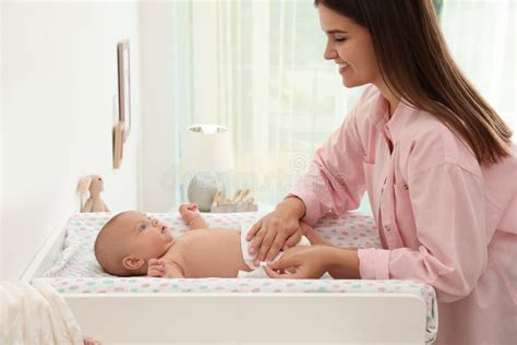 Madre Cambiando Pañales De Bebé En La Mesa En Casa Foto De Archivo