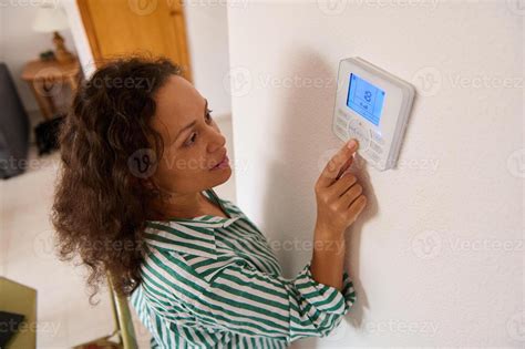 Woman Adjusting Smart Home Thermostat On Wall For Temperature Control 52536548 Stock Photo At