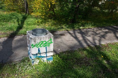 Concrete Trash Can With Scribbles Graffiti In Green Grass In Park