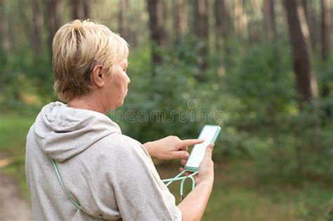 Middle Aged Woman In The Forest Takes Daily Steps Looks At The Route Map On Her Smartphone