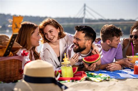 해변에서 피크닉을 즐기는 5명의 다인종 친구들 그들은 수박을 먹고 다채로운 칵테일을 마시고 그들 곁에는 기타가 있습니다 20