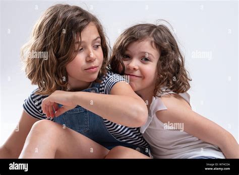 Two Attractive Young Sisters Cuddling Together With The Younger Little