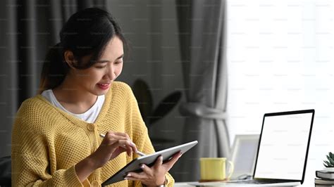 젊은 여성이 스타일러스 펜을 들고 태블릿 화면을 가리키며 사무실에서 흰색 화면이 있는 노트북 앞에 앉아 있다 사진 Unsplash의 태국 이미지