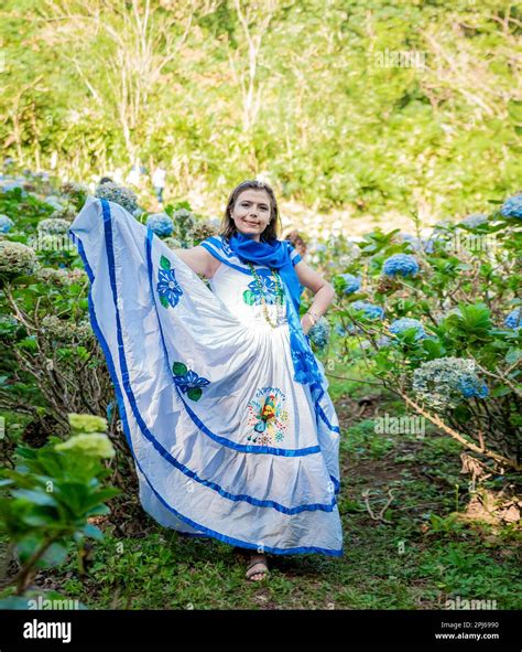 Smiling Woman In National Folk Costume In A Field Surrounded By Flowers