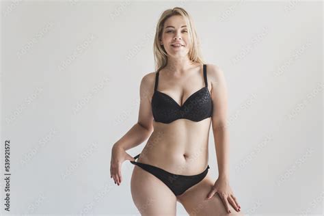 Young Chubby Woman With Fat Folds In Black Lingerie Rear View On A Gray