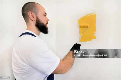 아파트에서 마무리 리노베이션을하고 건설 노동자와 핸디 건설 현장에 노란색으로 벽의 페인트 롤러 브러시 그림을 사용하여 전문 화가 홈 리노베이션 개념입니다 건설 산업에 대한