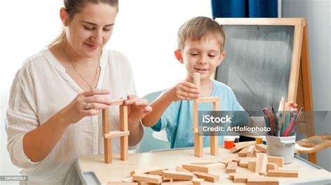 높은 장난감 나무 블록 타워 떨어지는 후 웃고 어머니와 어린 소년 어머니는 잠겨 있고 자기 고립되는 동안 집에서 자녀를 교육하고 가르친다 가족이 즐거운 시간을 보내고