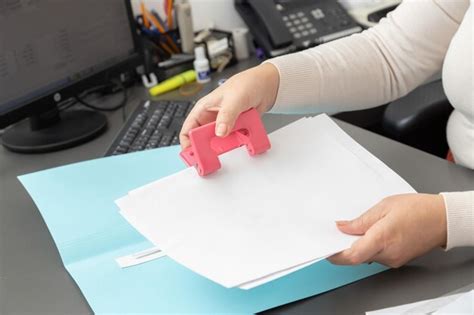 Premium Photo Woman Using A Hole Punch To Make Holes In Paper
