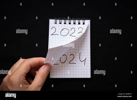 Notepad With Text 2023 And 2024 And The Hand Turns The Page Of The