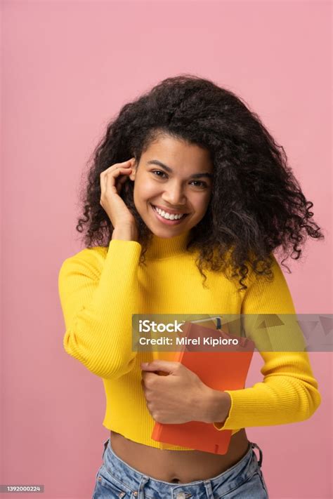 분홍색 배경에 고립 된 카메라를보고 책을 들고있는 아프리카 계 미국인 학생을 웃고 있습니다 학교로 돌아가기 교육 개념 20 24세에 대한 스톡 사진 및 기타 이미지 Istock