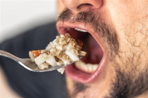 Um Homem Come Mingau Com Fruta A Boca Do Homem Está Aberta Foto Grátis