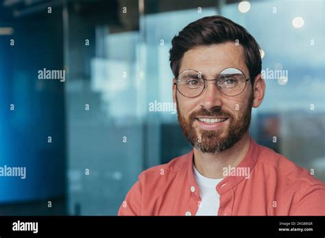 close up photo of happy and successful smiling programmer in red casual shirt man in glasses