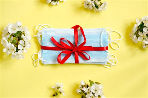 꽃과 노란색 배경에 의료 마스크 코로나 바이러스 보호 바이러스와 싸우는 선물 꽃 배경입니다 0명에 대한 스톡 사진 및 기타 이미지 Istock