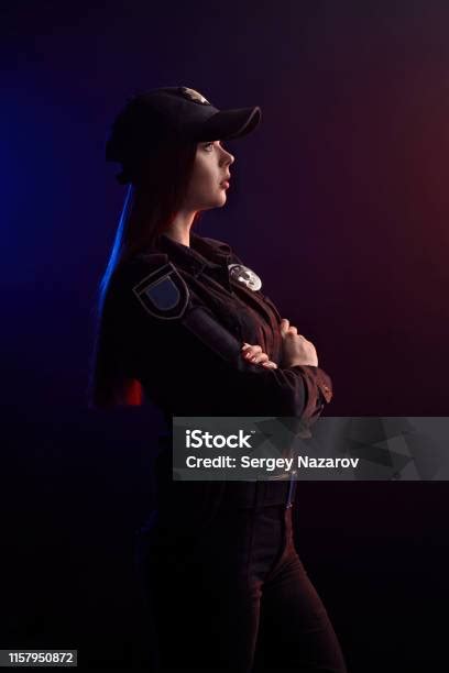 심각한 여성 경찰관은 빨간색과 파란색 백라이트와 검은 배경에 대한 카메라를 위해 포즈를 취하고있다 검은색에 대한 스톡 사진 및 기타 이미지 Istock