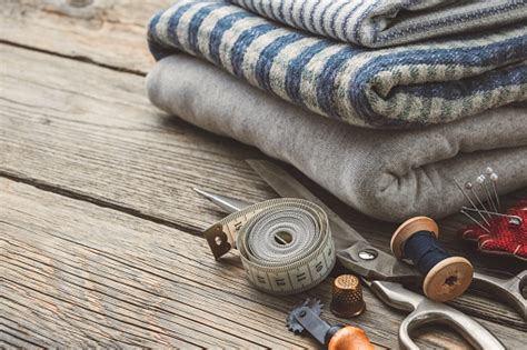 빈티지 바느질 항목 복고풍 테일러링 가위 측정 테이프 골무 실의 나무 스풀 핀 바늘 절단 칼과 나무 보드에 직물을 포함하는 쿠션