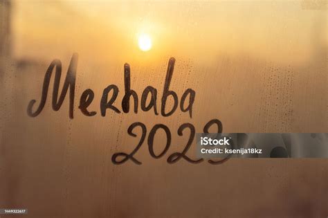 터키어로 된 글자 Merhaba는 영어로 안녕하세요 및 숫자 2023 주황색 일몰 창에 안개가 낀 비에 흩뿌려진 물 줄무늬가