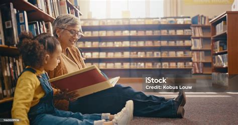 도서관 책 할머니는 학습 휴식 및 아동 발달을 위해 바닥에 손자와 함께 있습니다 교육 스토리텔링 할머니는 지상에서 소녀와 유대감을 형성하고 함께 책을 읽고 즐거운 시간을