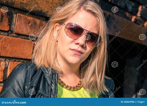 Young Confident Woman With Blonde Hair Standing Against A Brick Stock