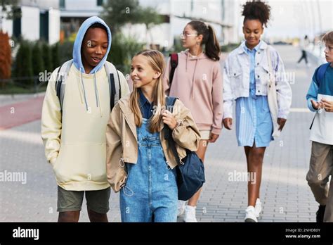 Cute Intercultural School Learners With Backpacks Chatting On Their Way Home After Classes While