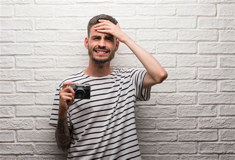 젊은 남자 머리 수치심과 깜짝 얼굴로 충격된에 손으로 압박 흰색 벽돌 벽에 빈티지 카메라 서 들고 분노 하 고 좌절 두려워 하 고 실수에 대 한 화가 감정에 대한 스톡 사진