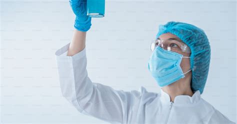 임상 실험을 하고 백신 용액을 검색하고 파란색 액체가 담긴 의료용 유리병을 들고 샘플을 확인하고 흰색 배경에 격리된