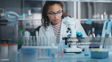 의학 실험실 현미경을 사용하여 아름다운 흑인 과학자의 초상화 테스트 샘플의 분석을 수행합니다 야심찬 젊은 생명 공학 전문가 첨단 장비와 협력 여자에 대한 스톡 사진 및 기타